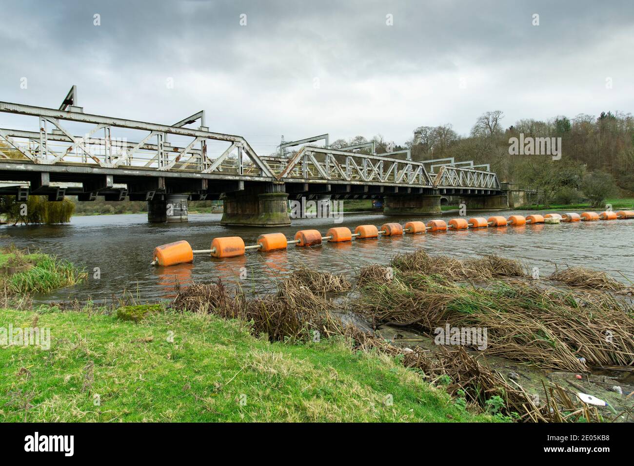 Orange safety boom stretched across a river in front of a railway ...