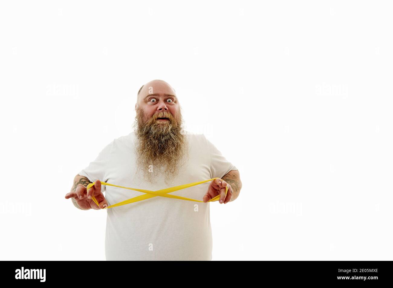 A smiling ovrweigh man twisting a fitness elastic band in the shape of ...