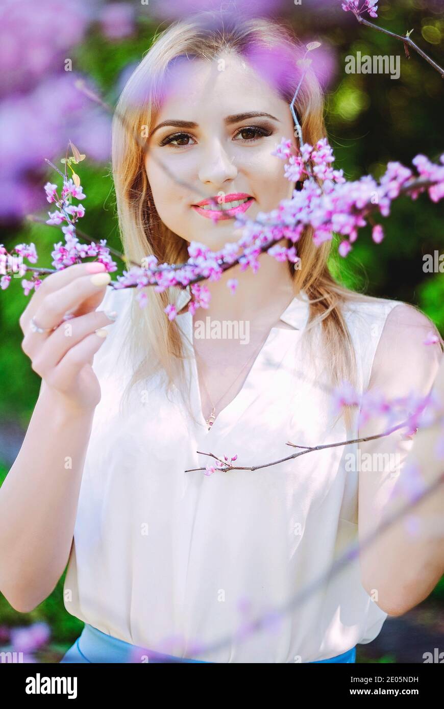 Portrait of young attractive woman in spring garden with blooming pink ...