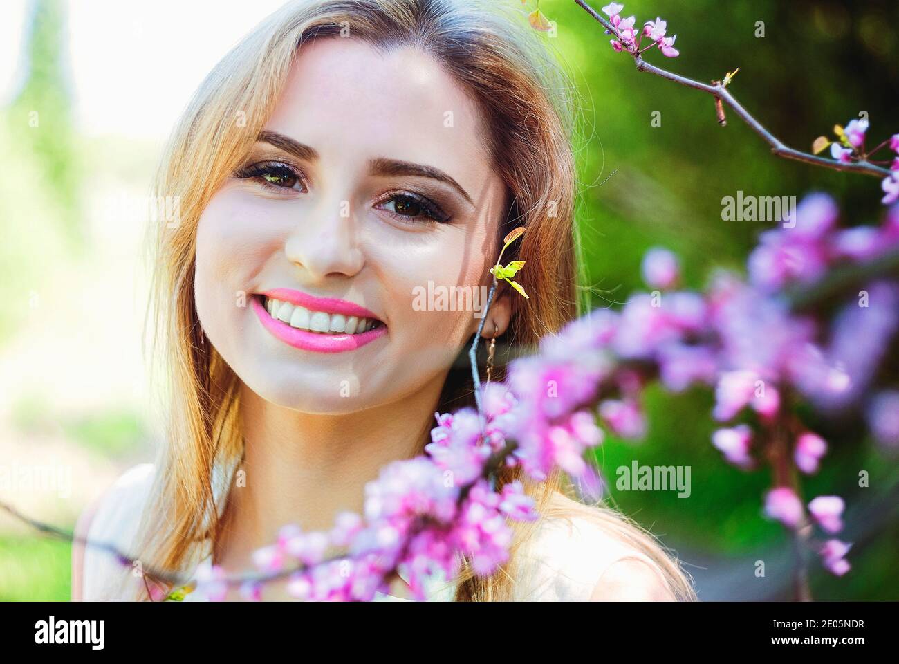 Portrait of young attractive woman in spring garden with blooming pink ...
