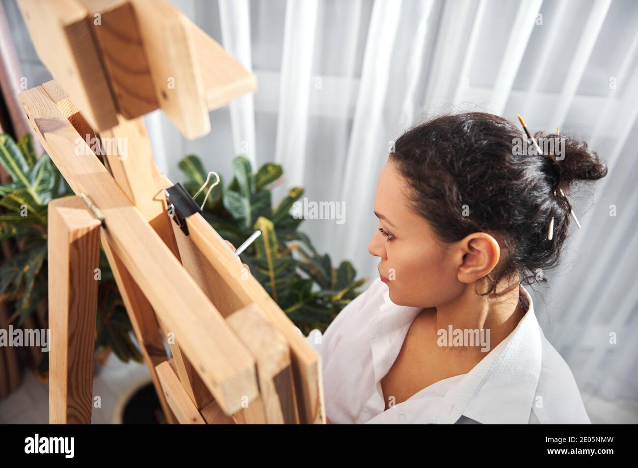 Top view of a beautiful brunette painter with gathered hair in a bun ...