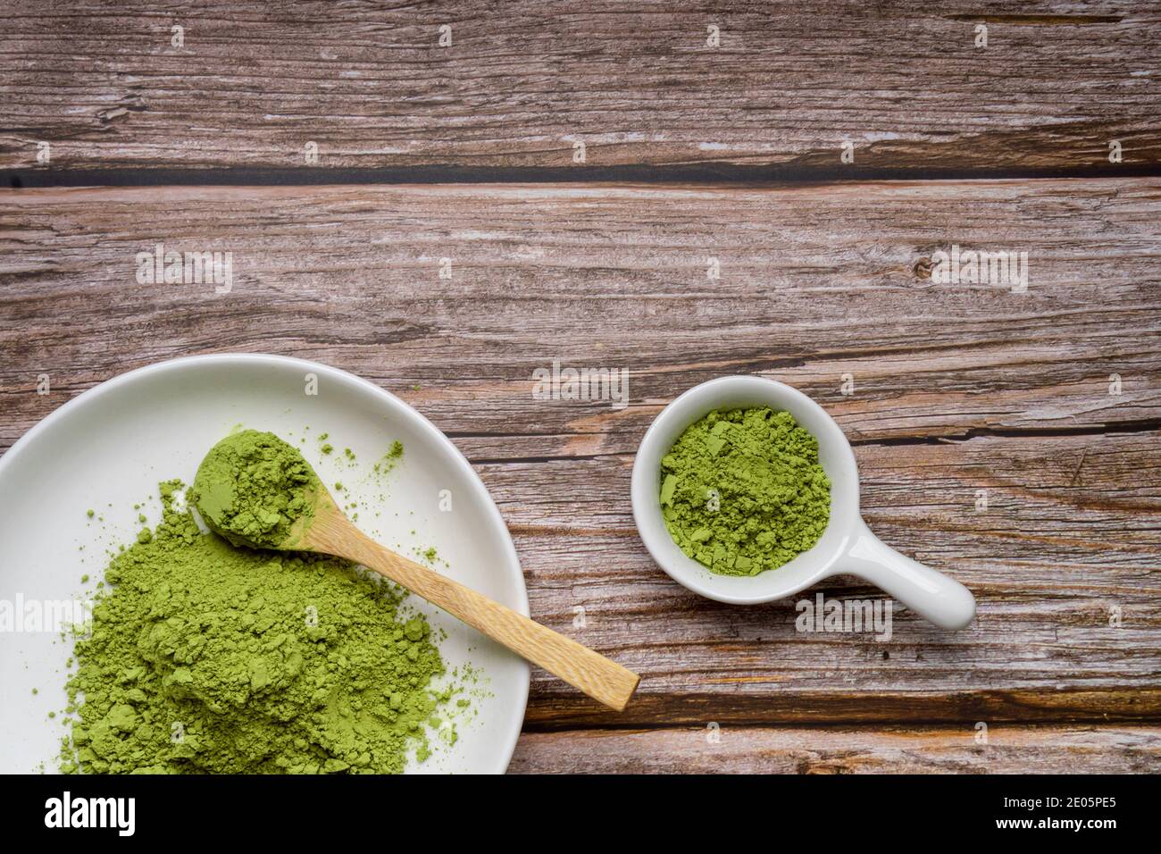 matcha green tea powder in bowl with wood spoon on wooden table. Top ...