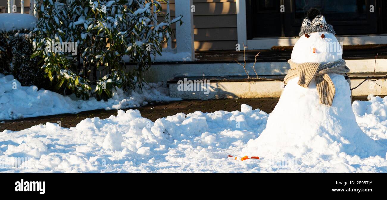 A small snowman on the front lawn of a residetial home after a December ...