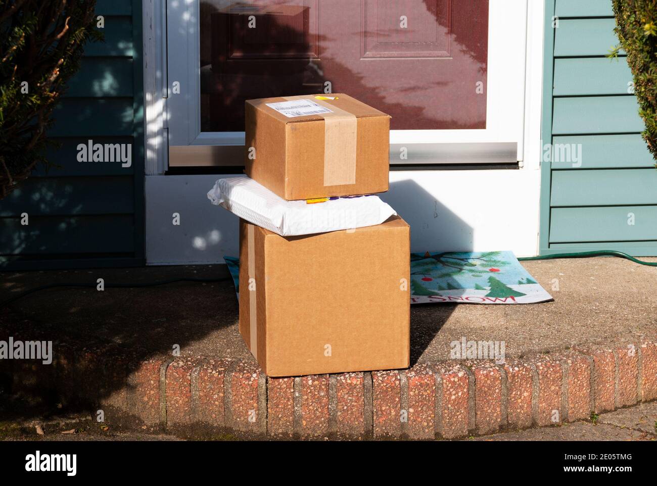 Three packages are delivered to the frint stoop of a residential house ...