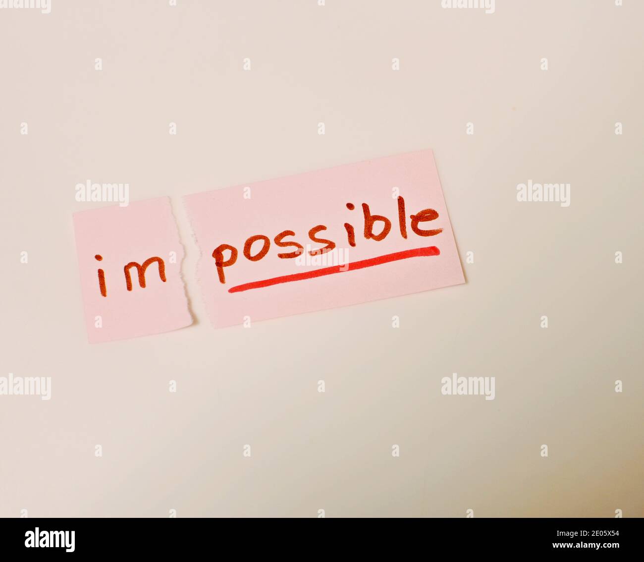 Concept of the word impossible written by hand and cut as possible, put ...