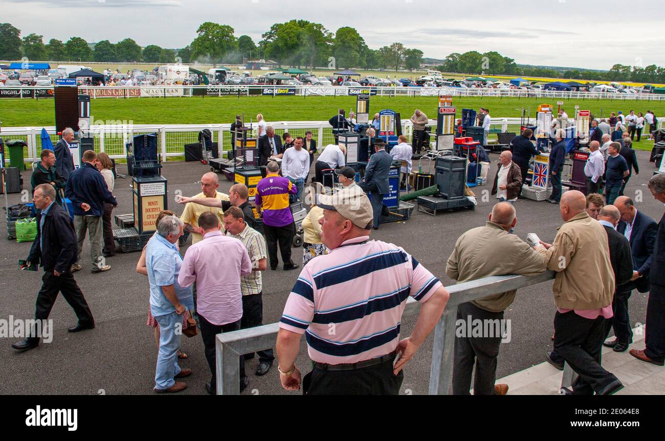 Spectators gathering together along the main racecourse stands to watch ...