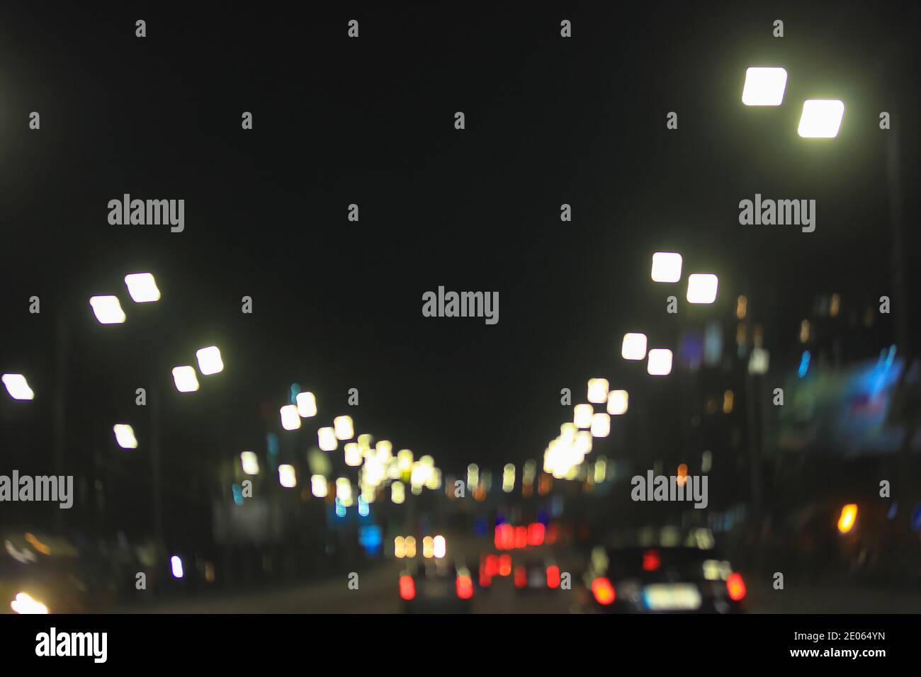 Cars on the road in the city at night and neon lights of headlights and ...