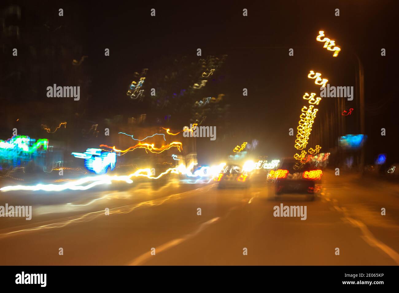 Cars on the road in the city at night and neon lights of headlights and ...