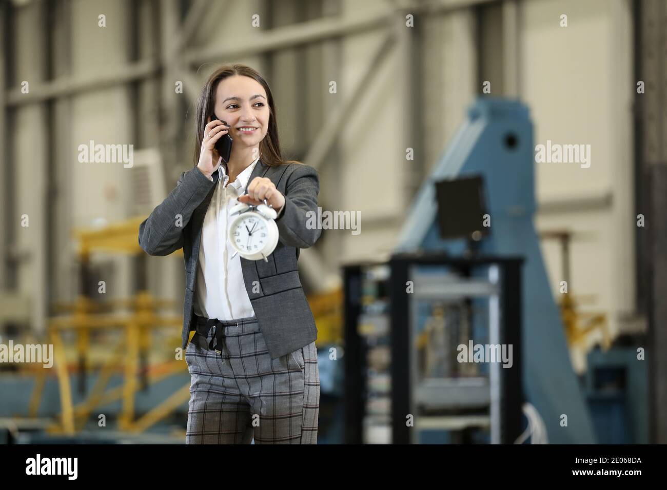 Portrait of a female factory manager in a business suit holding mobile ...