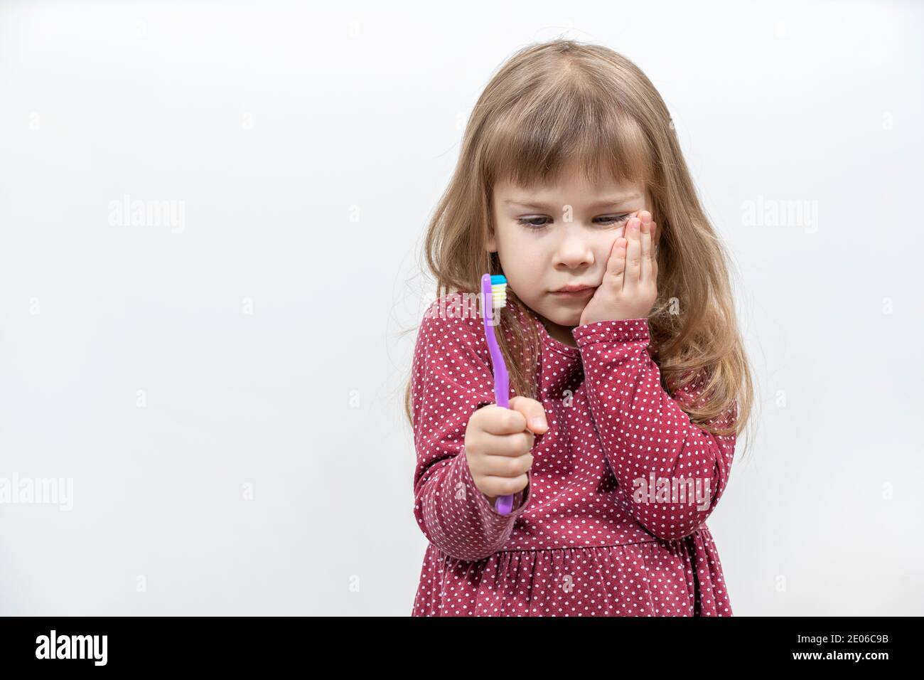 sad little girl having a toothache. the child is holding a cheek, in ...