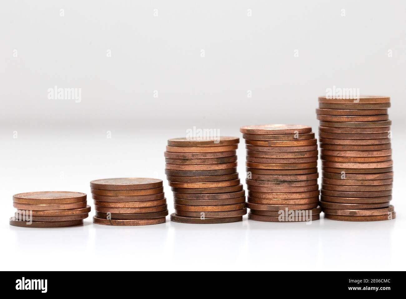 Side view of stacks of coins increasing in height, on white studio ...