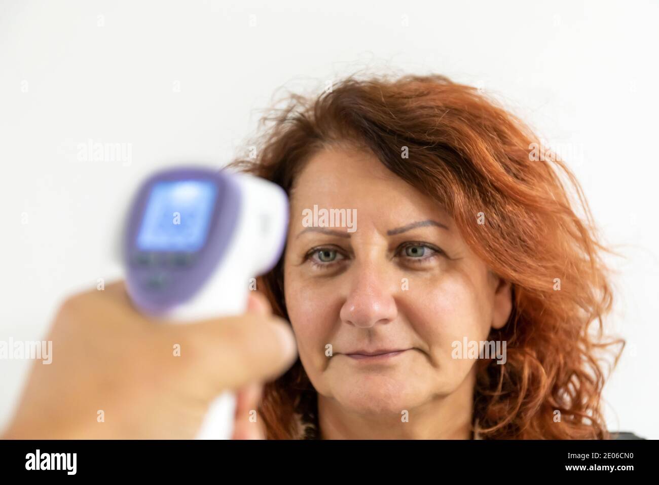 Measure a woman's body temperature using an electronic gun device Stock ...