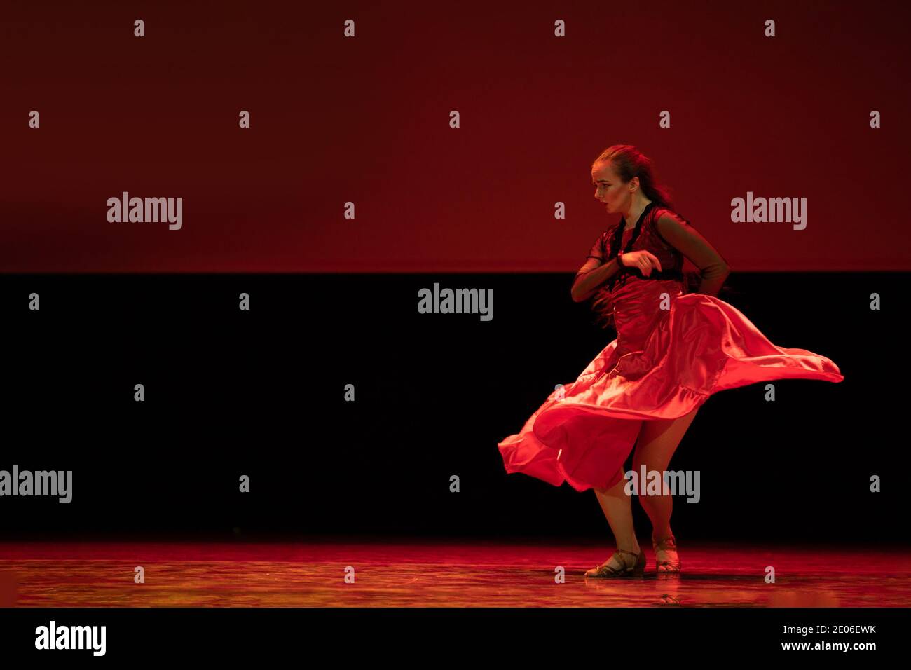 Dancer in a red dress dancing Spanish flamenco on the stage in the ...