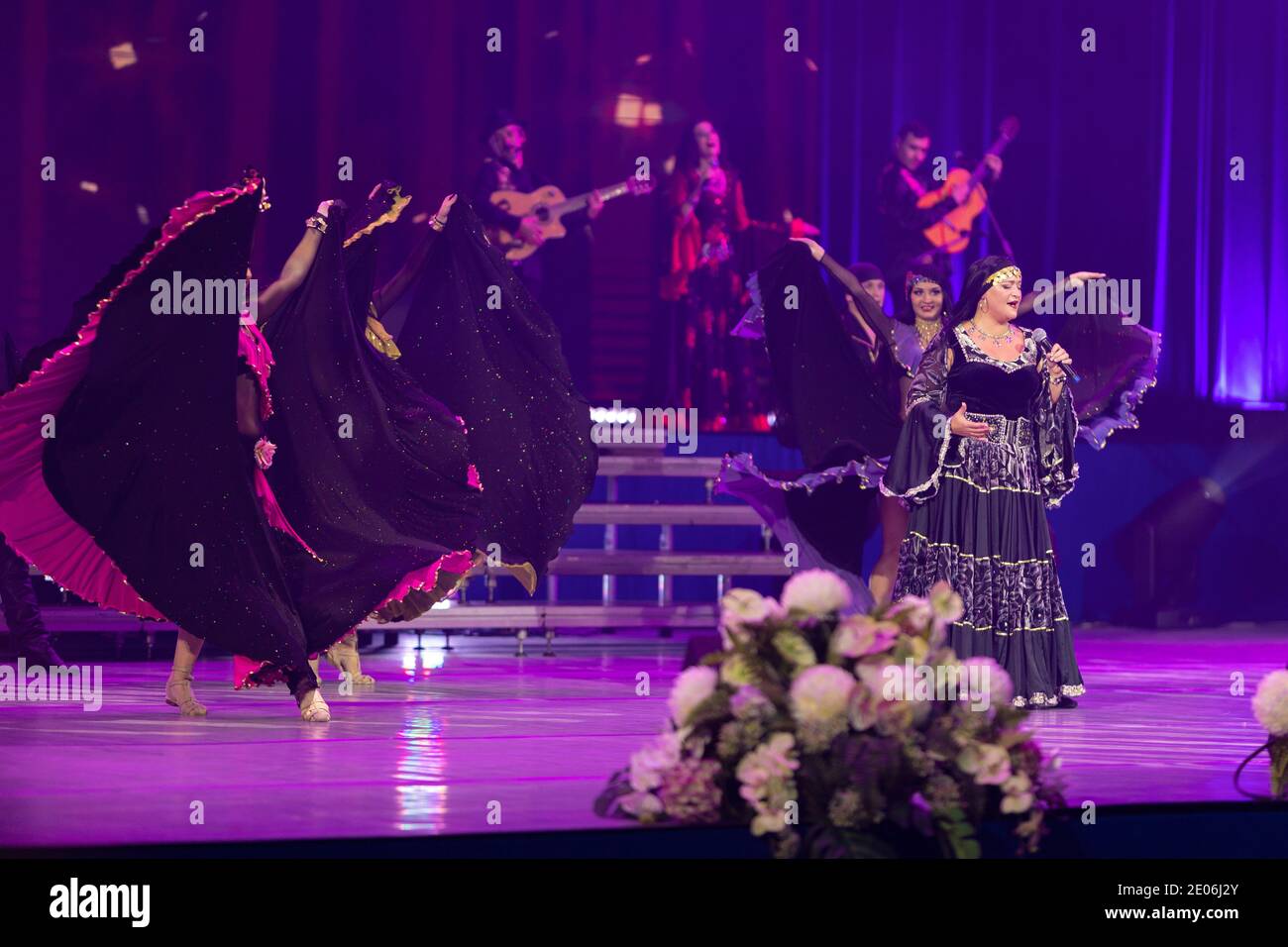 A team of musicians and singers perform on stage in front of the ...