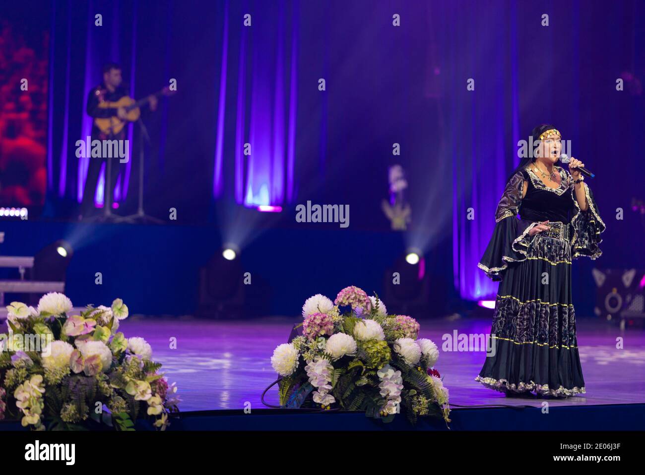 A team of musicians and singers perform on stage in front of the ...