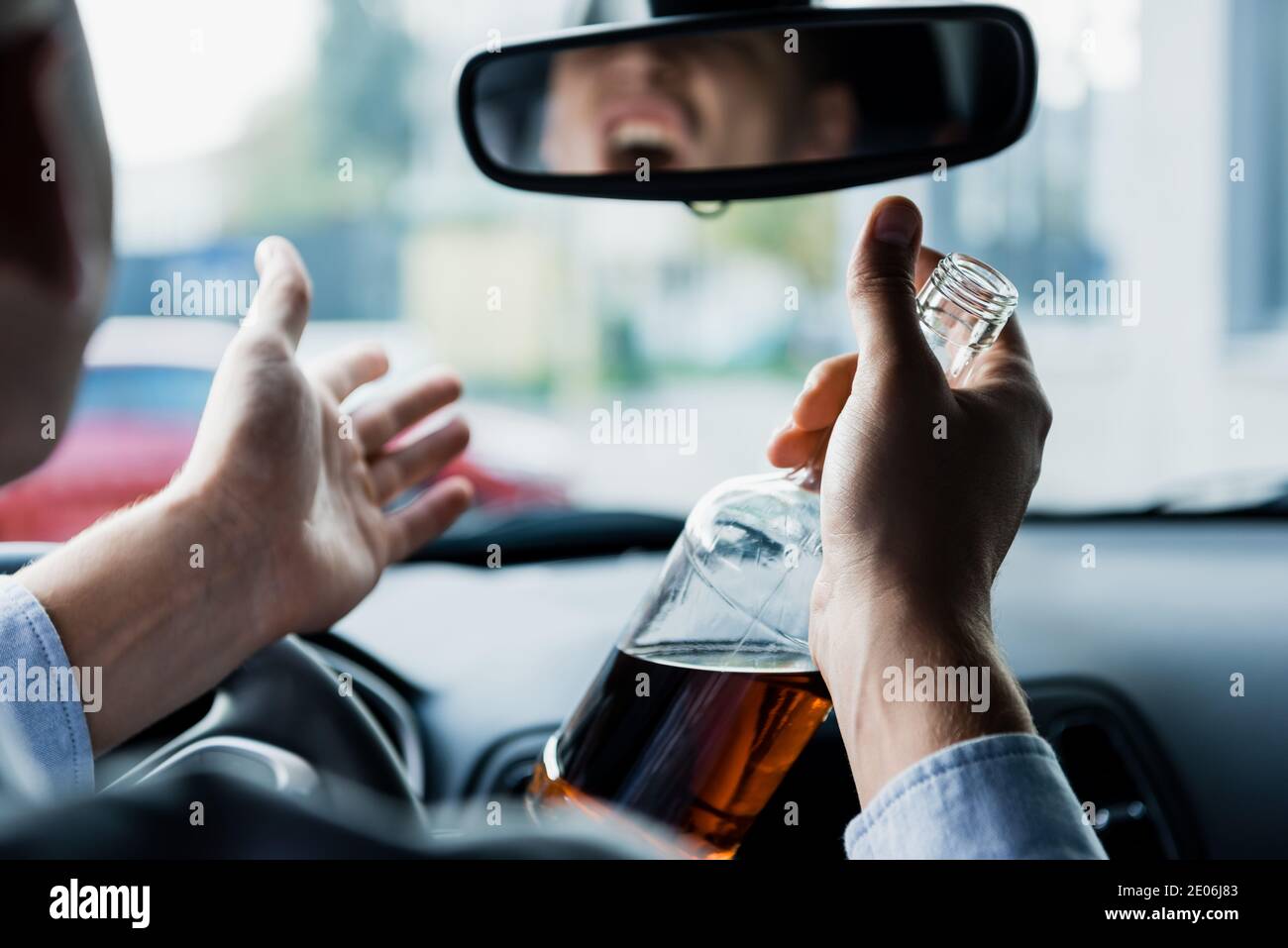 partial view of angry drunk man with bottle of whiskey shouting and ...