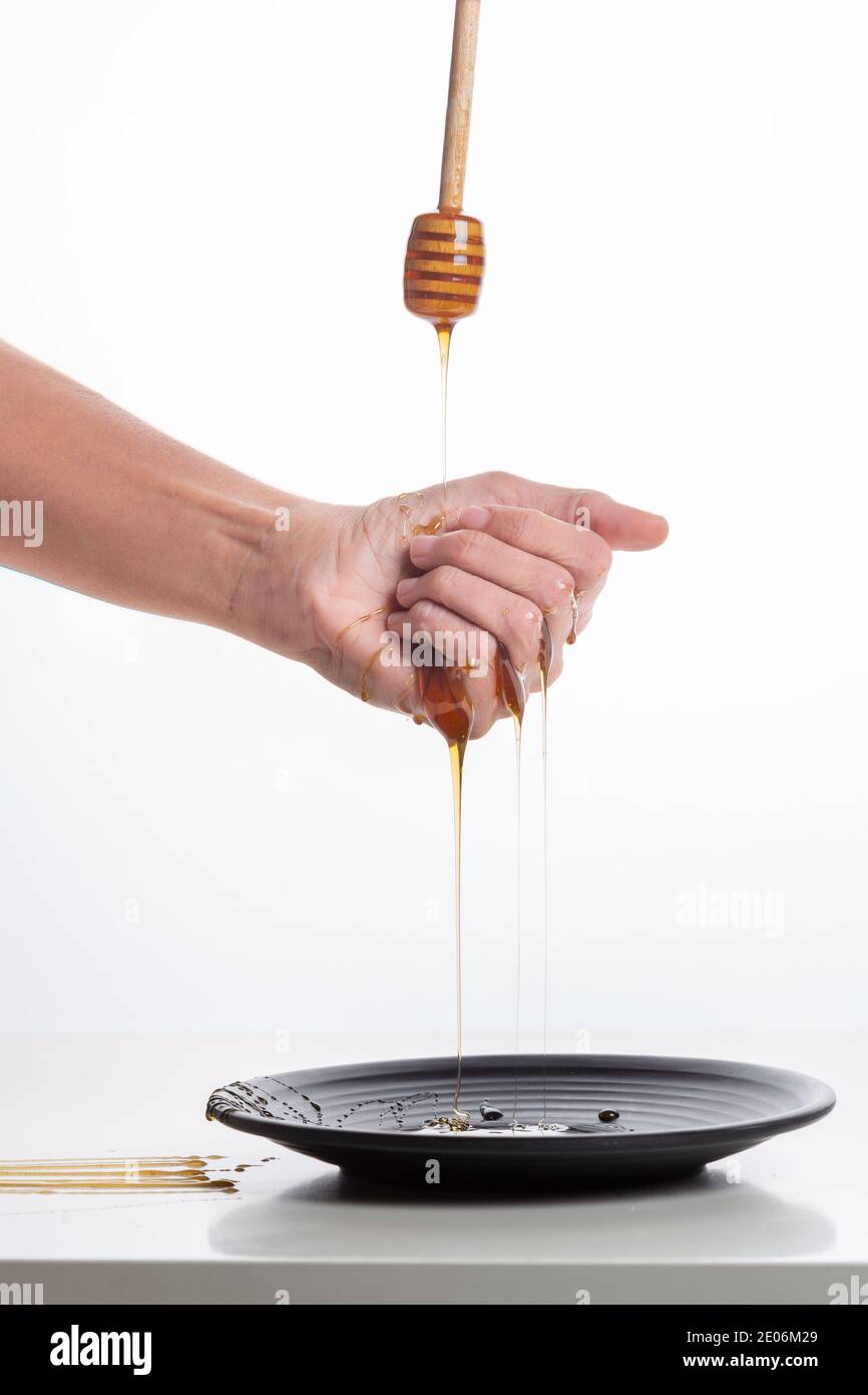 Stick spilling honey on hand on white background Stock Photo - Alamy