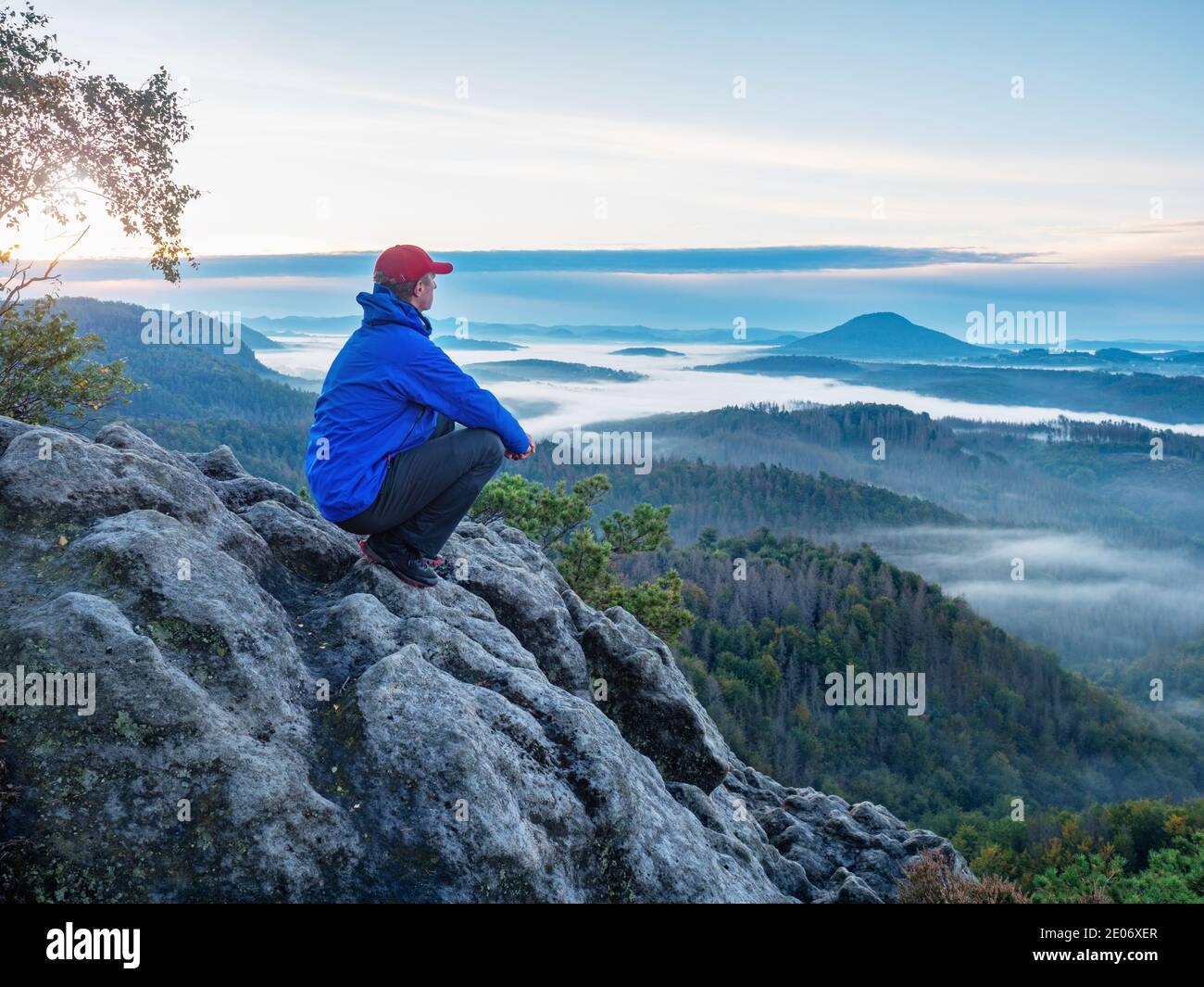 Moment of daybreak. Man sit on rock and watching into colorful mist and ...