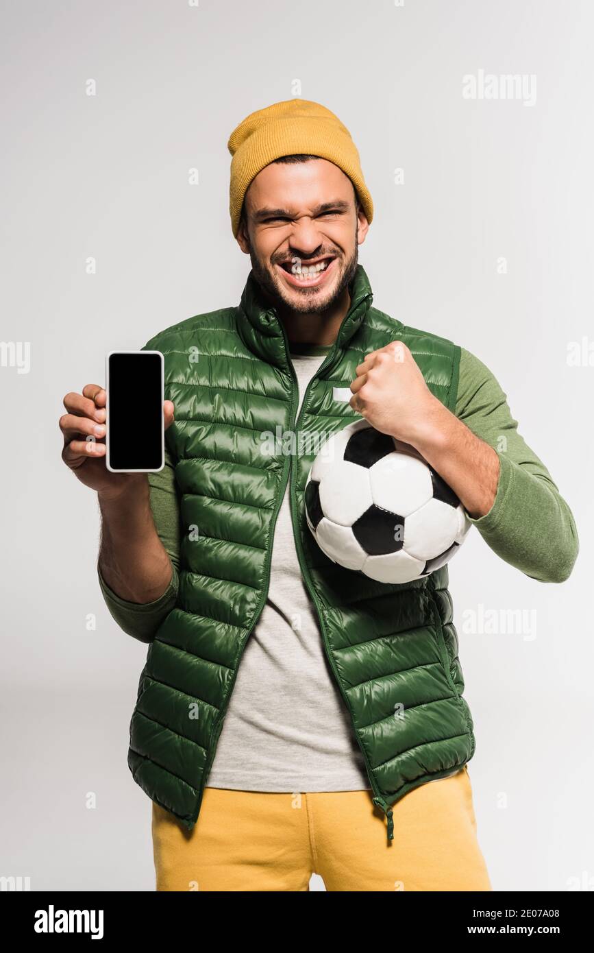 Cheerful sportsman showing yeah gesture and holding smartphone with ...