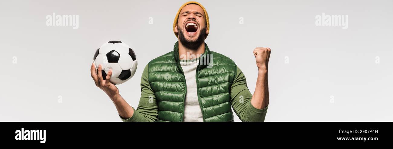 Excited sportsman with football showing yes gesture isolated on grey ...