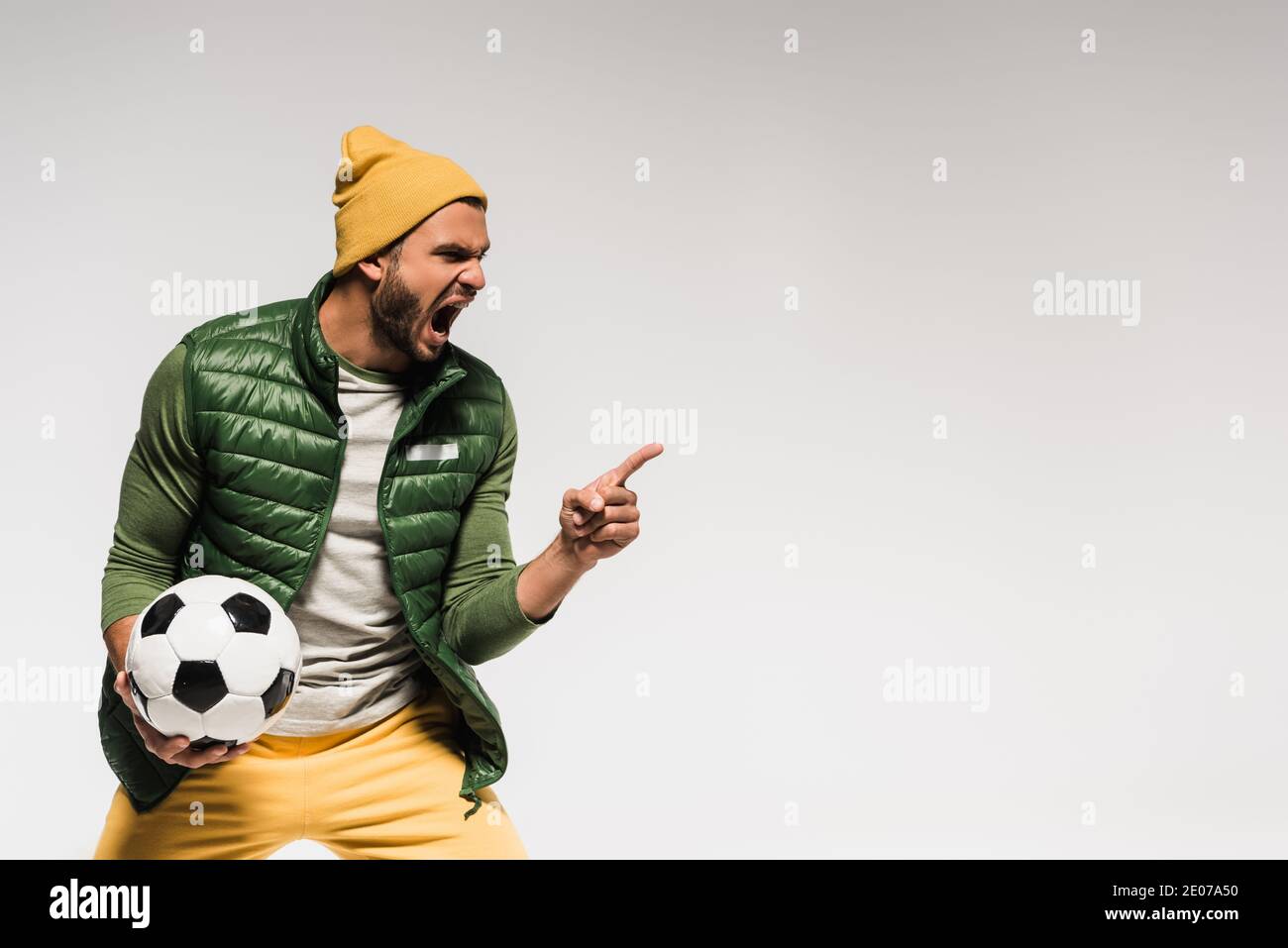Aggressive sportsman holding football while screaming and pointing with ...