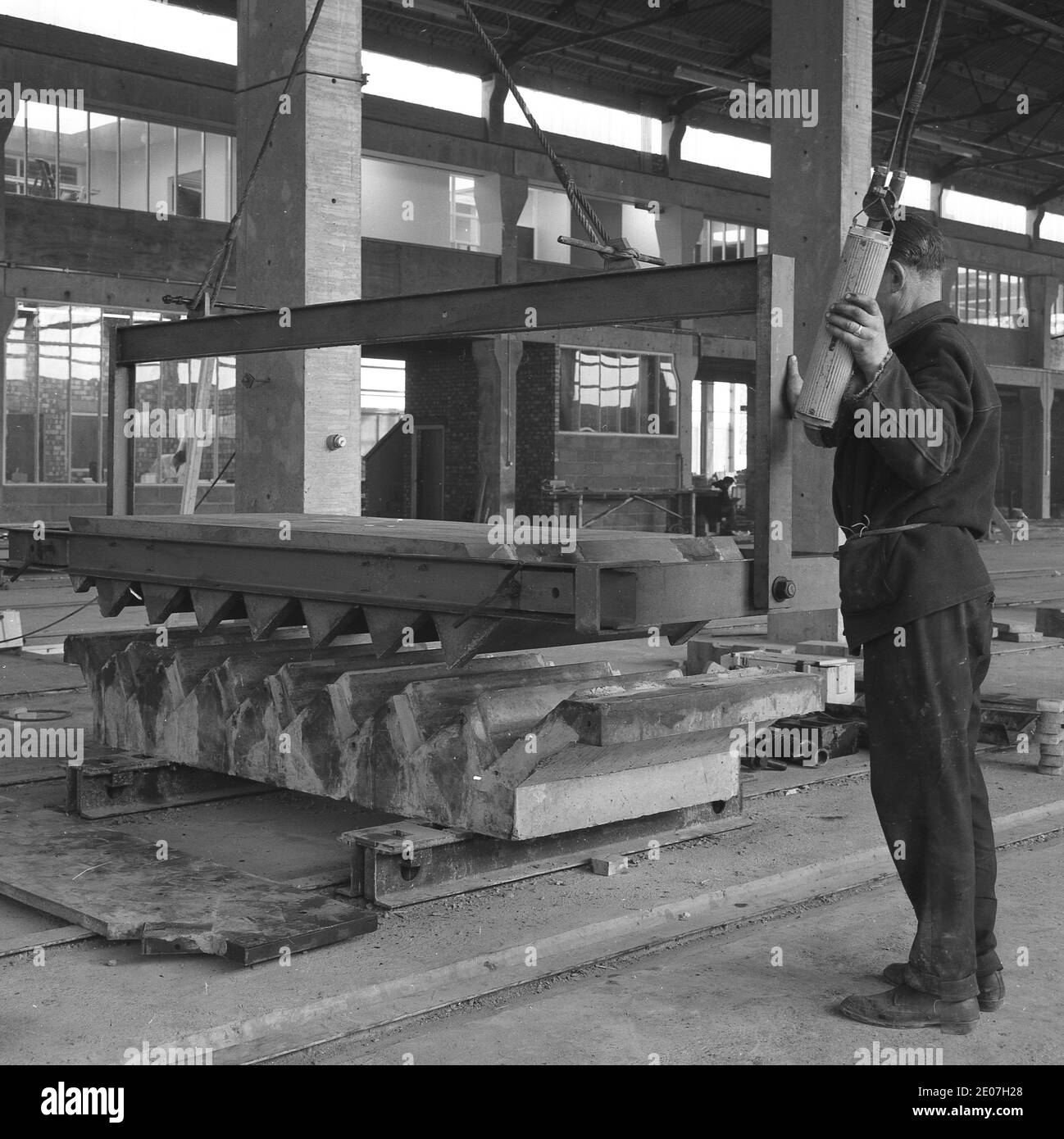 1960s, historical, in a large industrial unit, a workman moving a steel ...