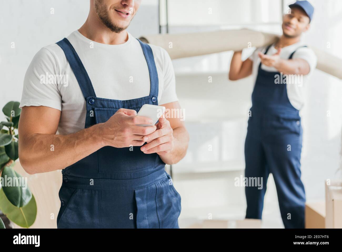 handyman using smartphone near indian mover on blurred background Stock ...