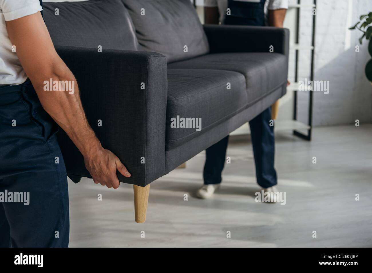 partial view of workers carrying heavy sofa in apartment Stock Photo ...