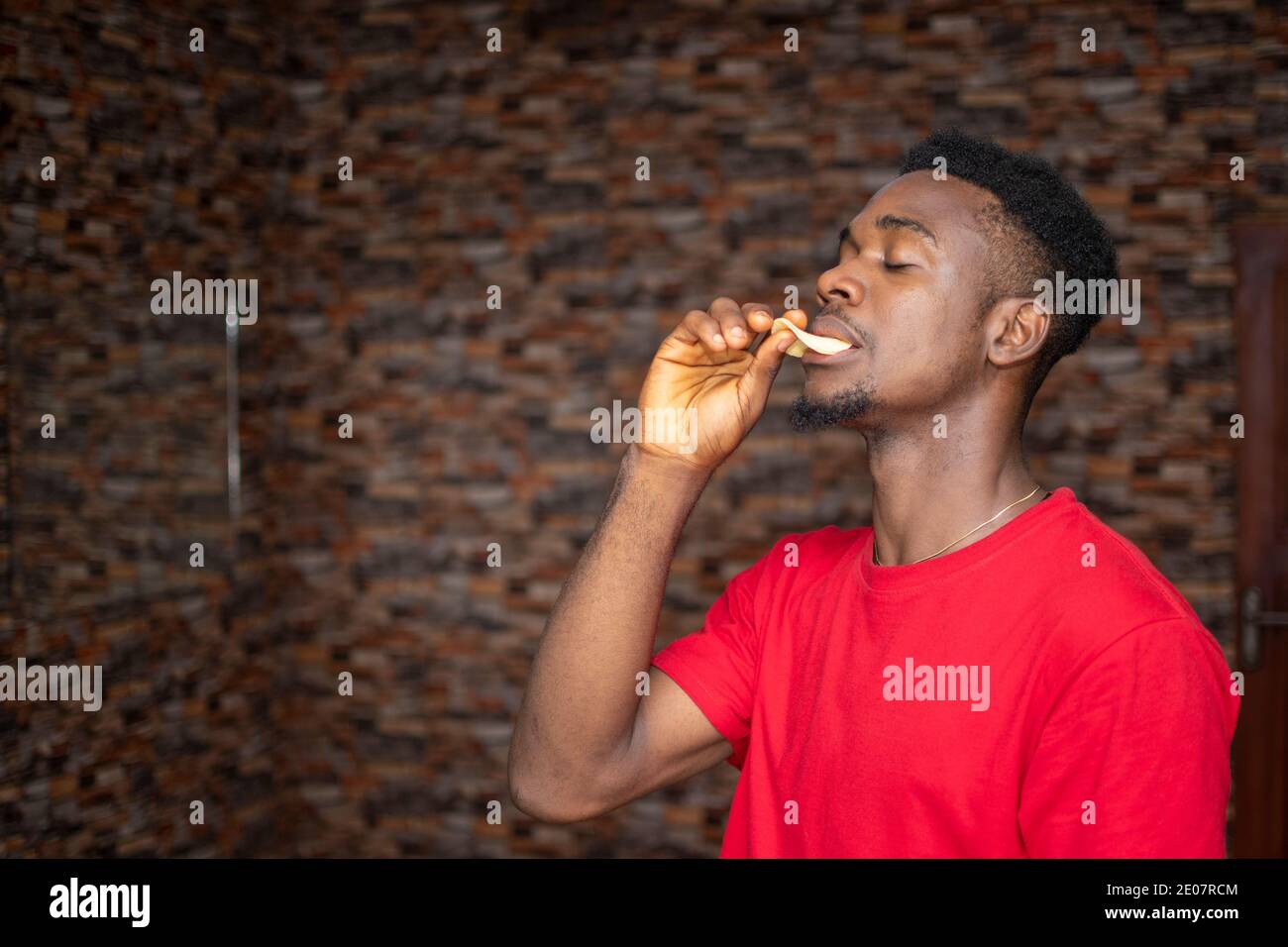 young african man eating chips Stock Photo - Alamy