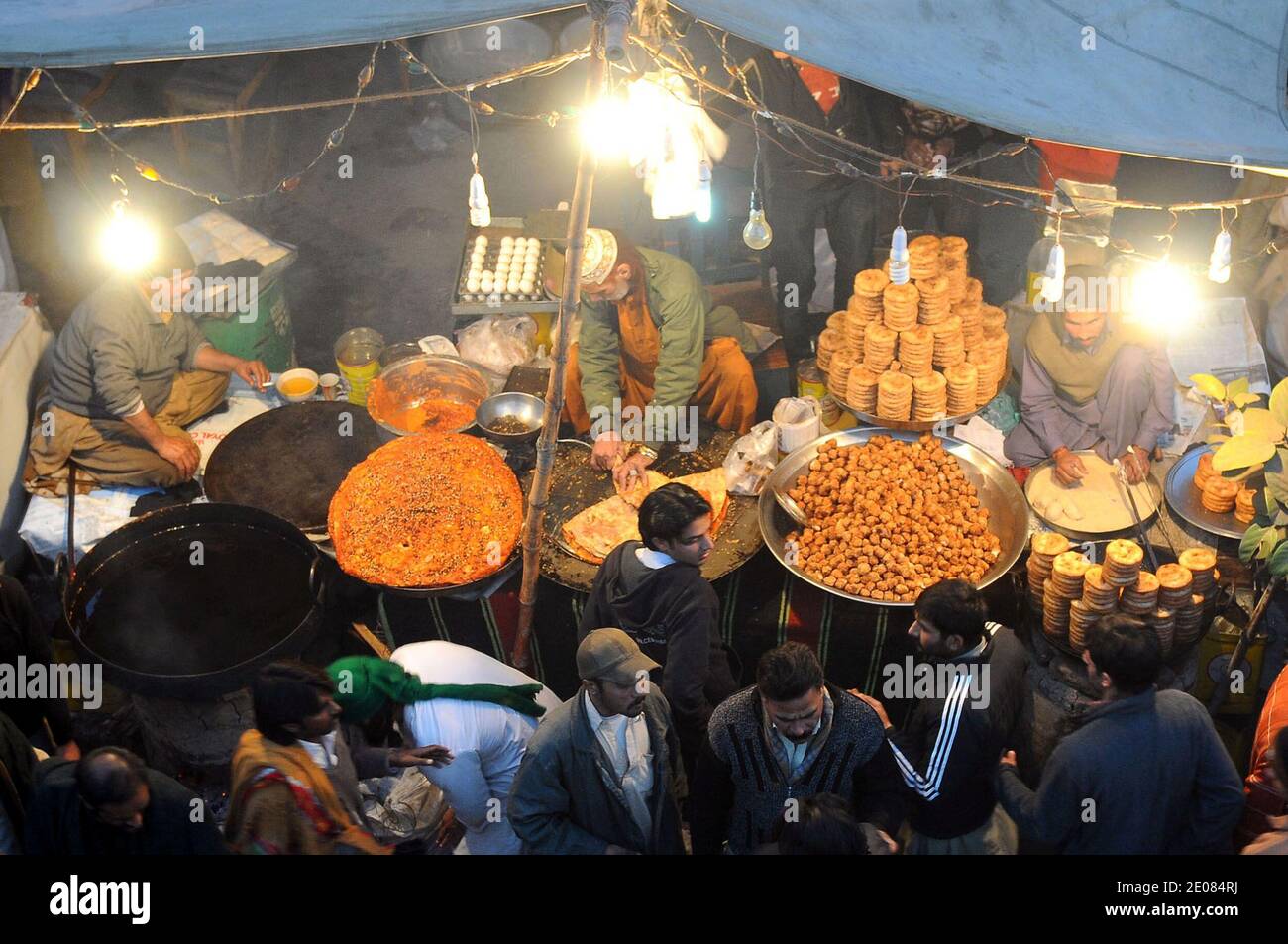A Pakistani cook prepares a traditional big bread outside shrine of a ...