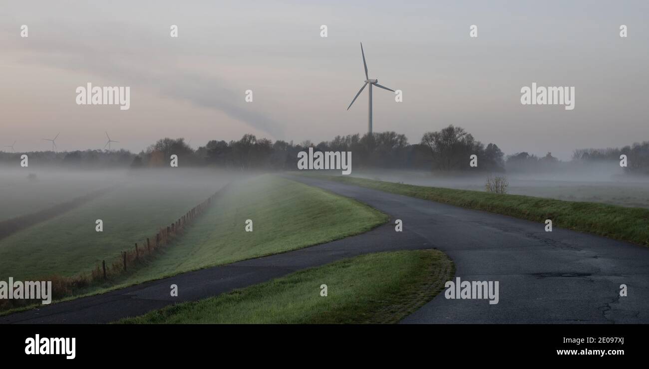 misty morning in an agricultural landscape with wind turbines, rural ...