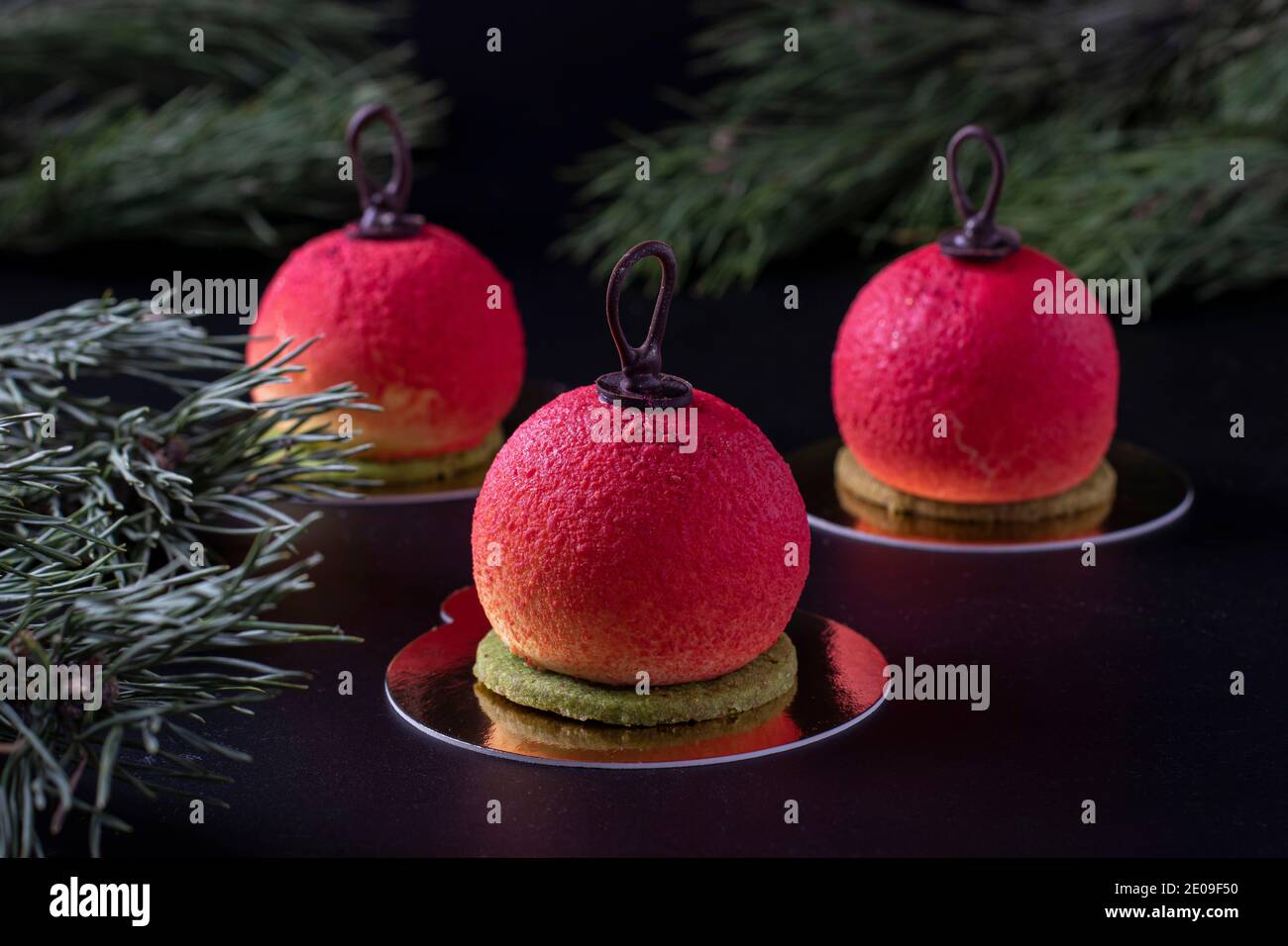 Three mousse desserts in the form of Christmas balls on a dark ...