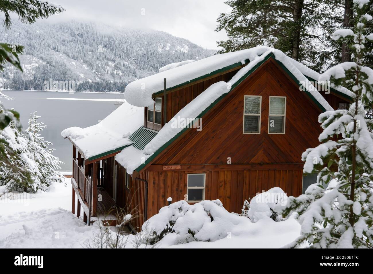 Winter Cottage on a lake with snow on roof and trees Stock Photo - Alamy