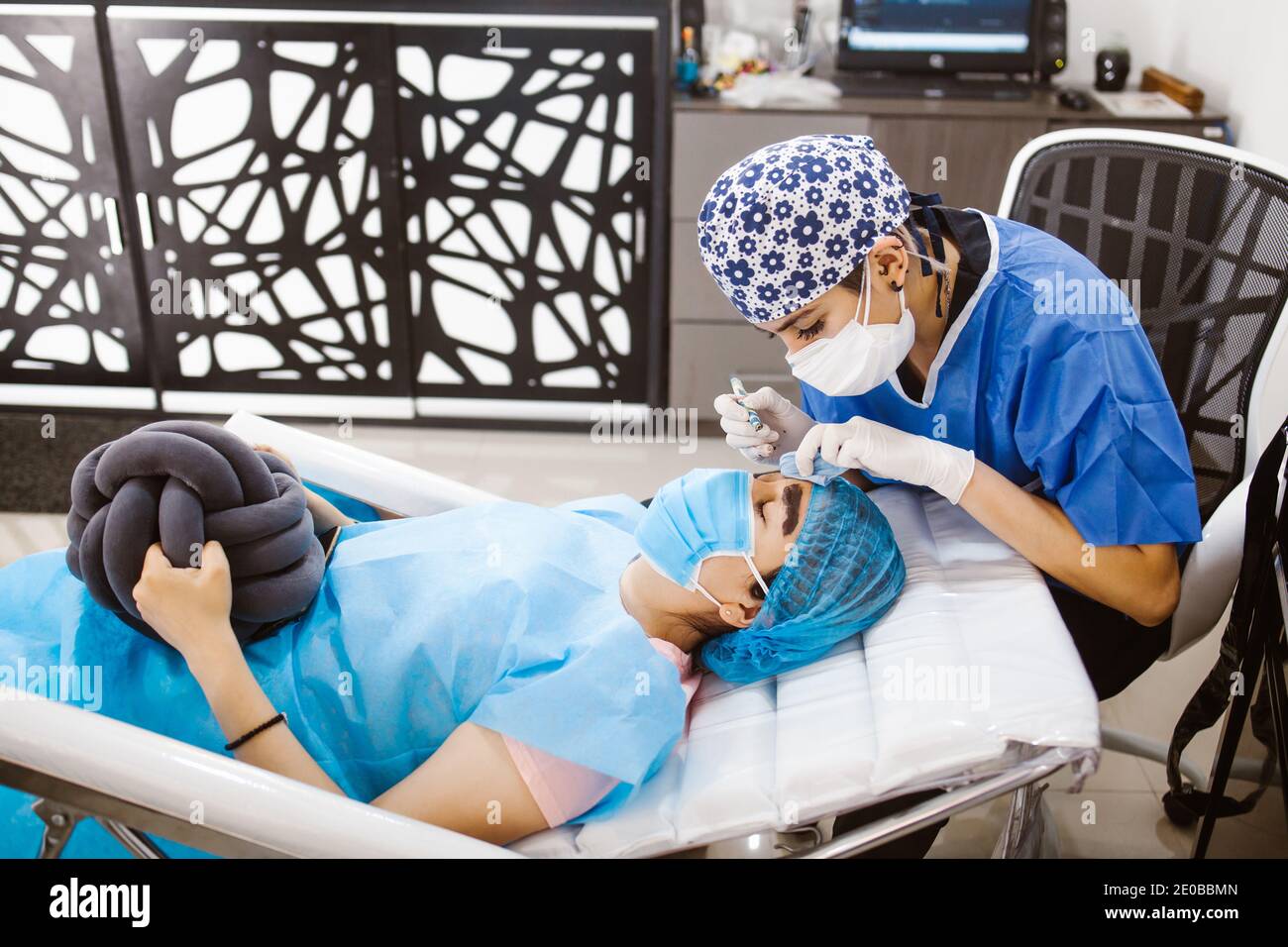 Latin Cosmetologist preparing to mexican woman for eyebrow permanent ...