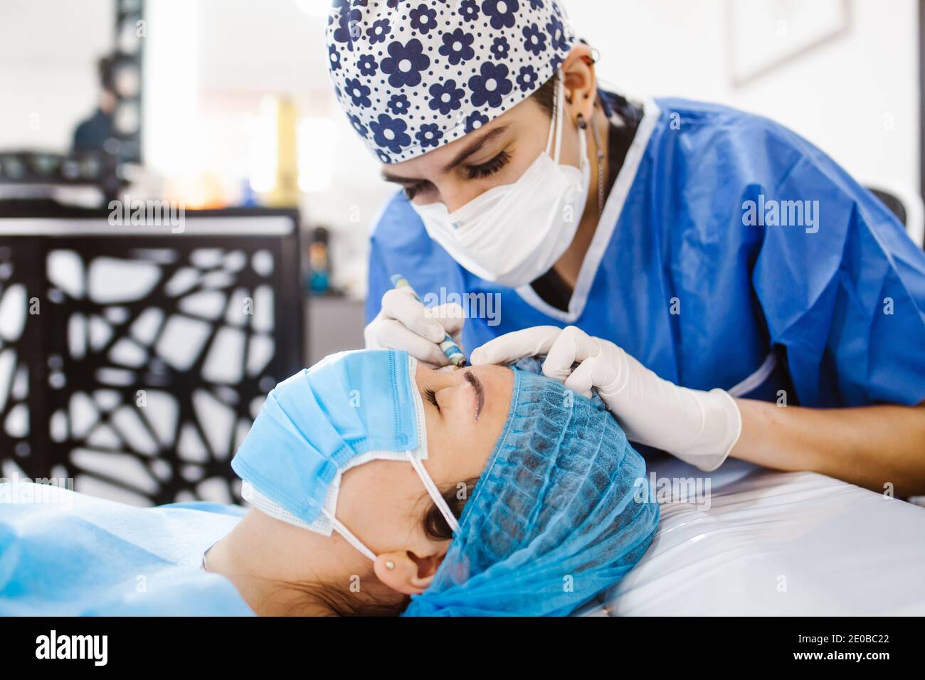 Latin Cosmetologist preparing to mexican woman for eyebrow permanent ...