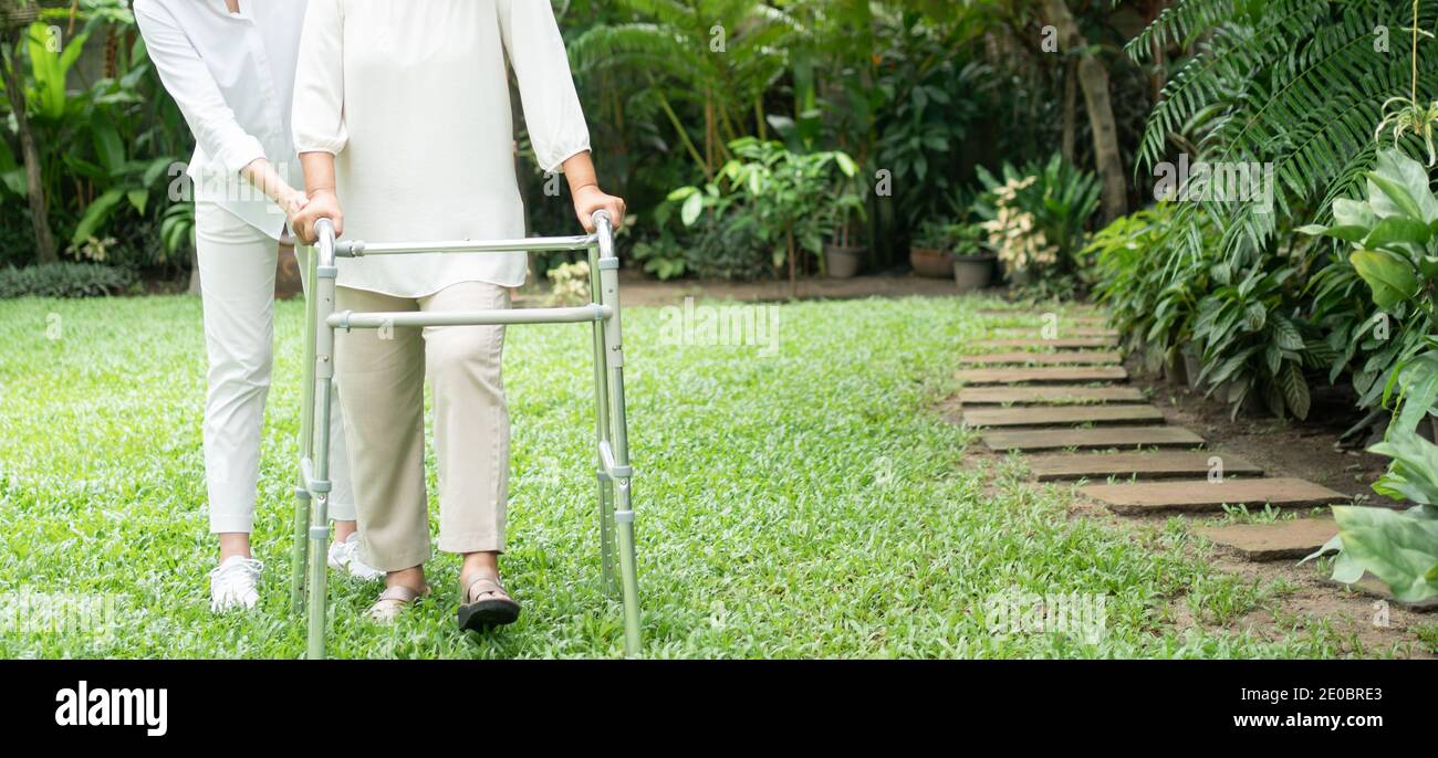 An old elderly Asian woman uses a walker and walking in the backyard ...