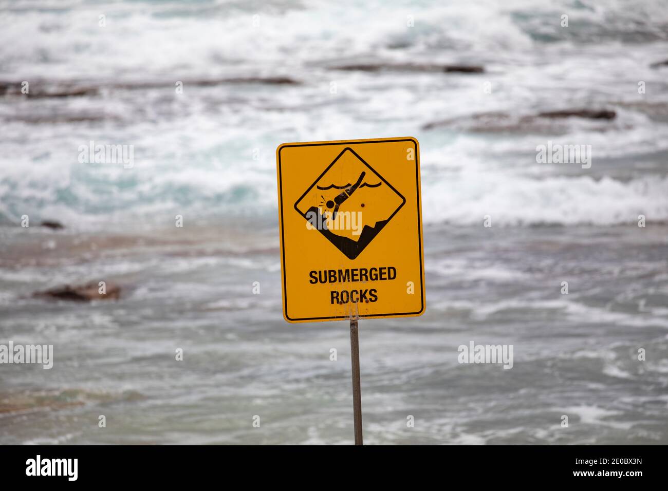 Warning submerged rocks sign advising people not to dive in the ocean ...