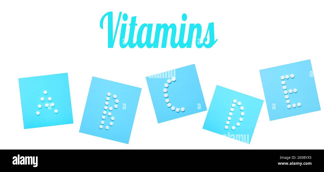 Vitamins A, B, C, D, E. Letter A, B, C, D, E from white pills on blue ...