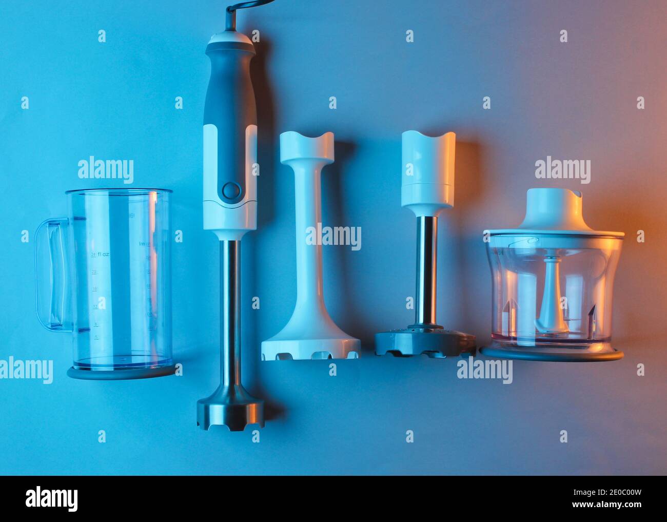 Electric hand blender with nozzles on neon blue orange light background ...