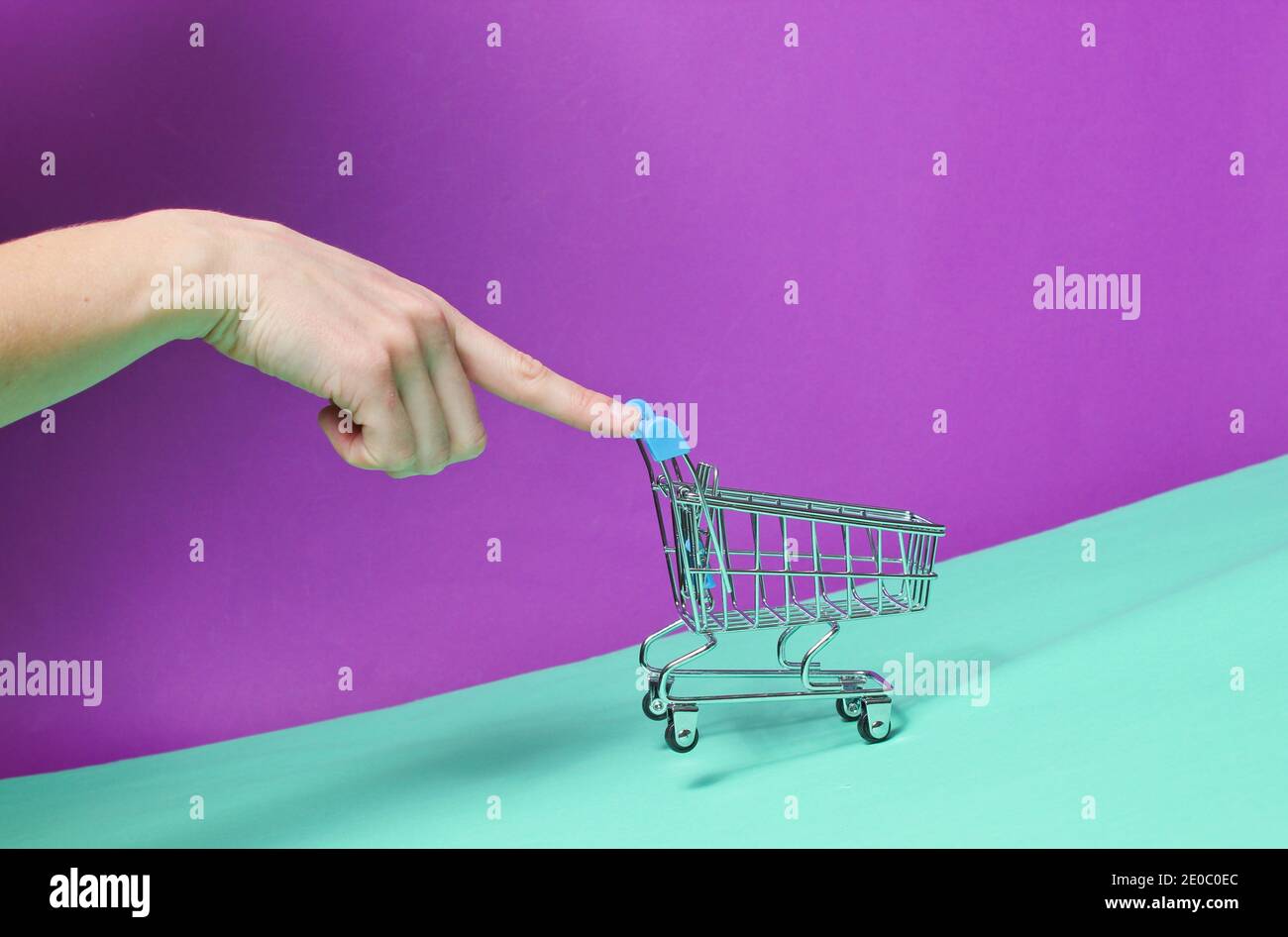 Female finger pushes up sloping empty mini shopping trolley. Shopping ...