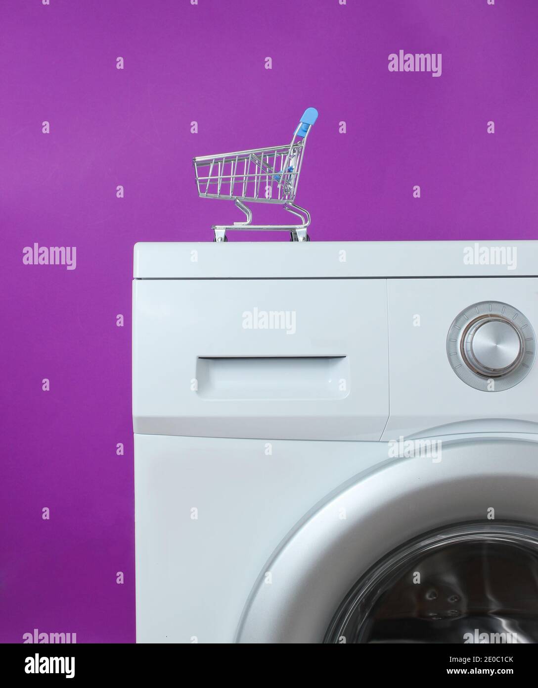 Mini shopping cart on washing machine against purple background ...