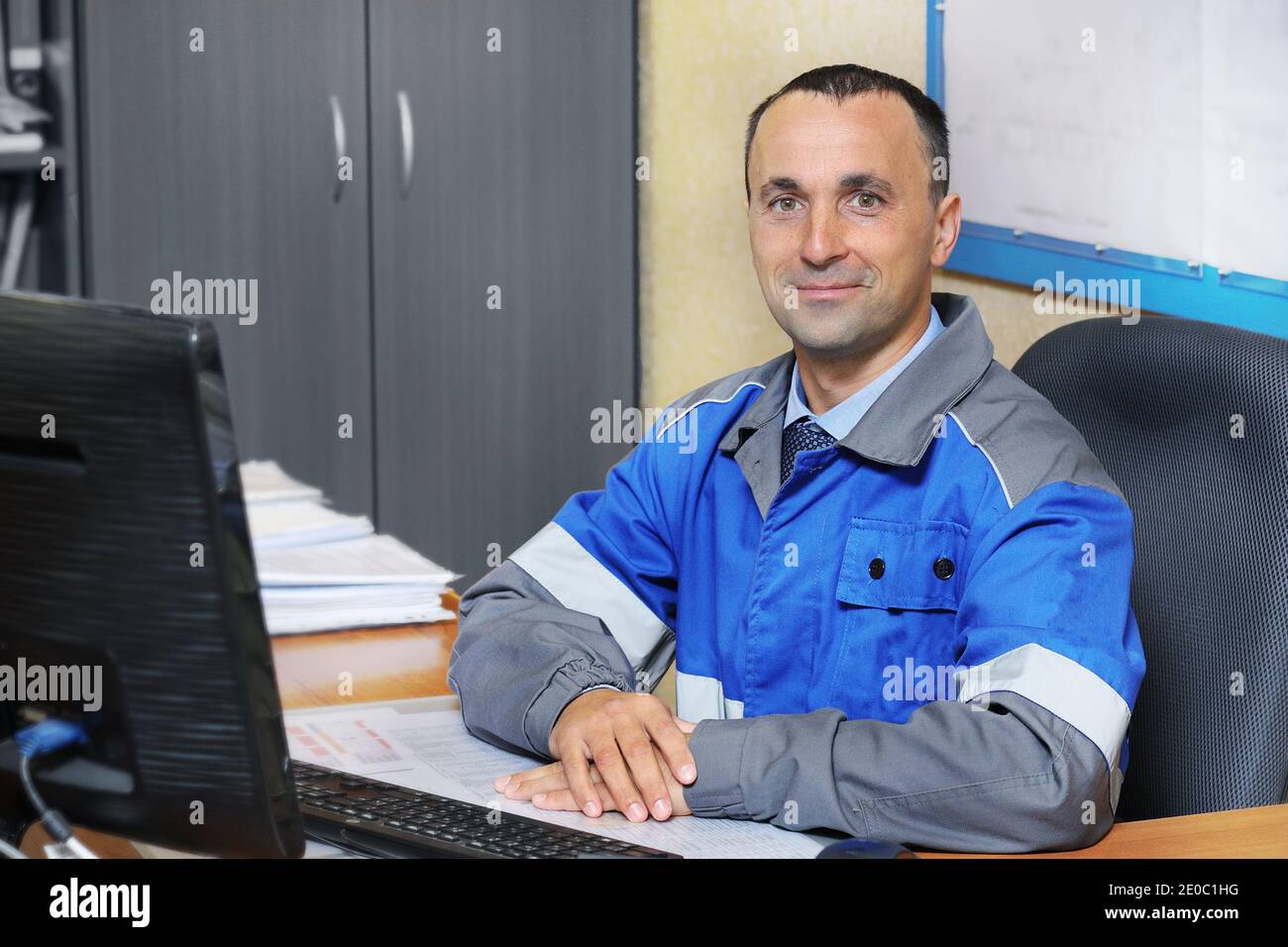Happy engineer sitting at his Desk in a chair. Portrait of a production ...