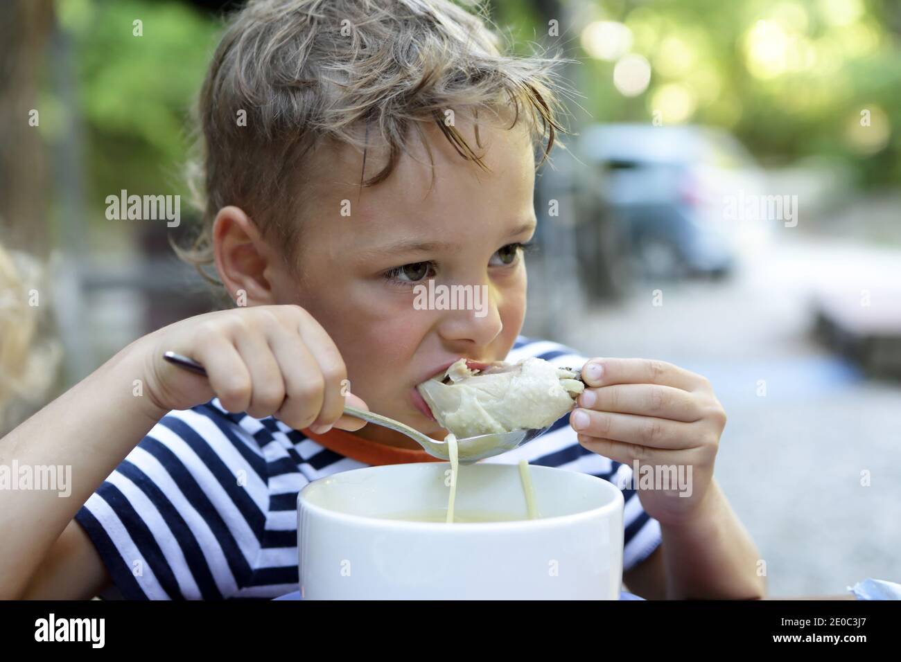 Kid eating chicken soup in a restaurant Stock Photo - Alamy