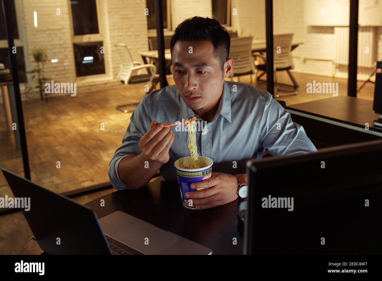Young men in the office to work overtime to eat instant noodles Stock ...