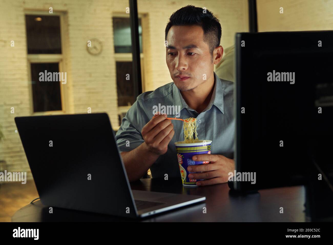 Young men in the office to work overtime to eat instant noodles Stock ...