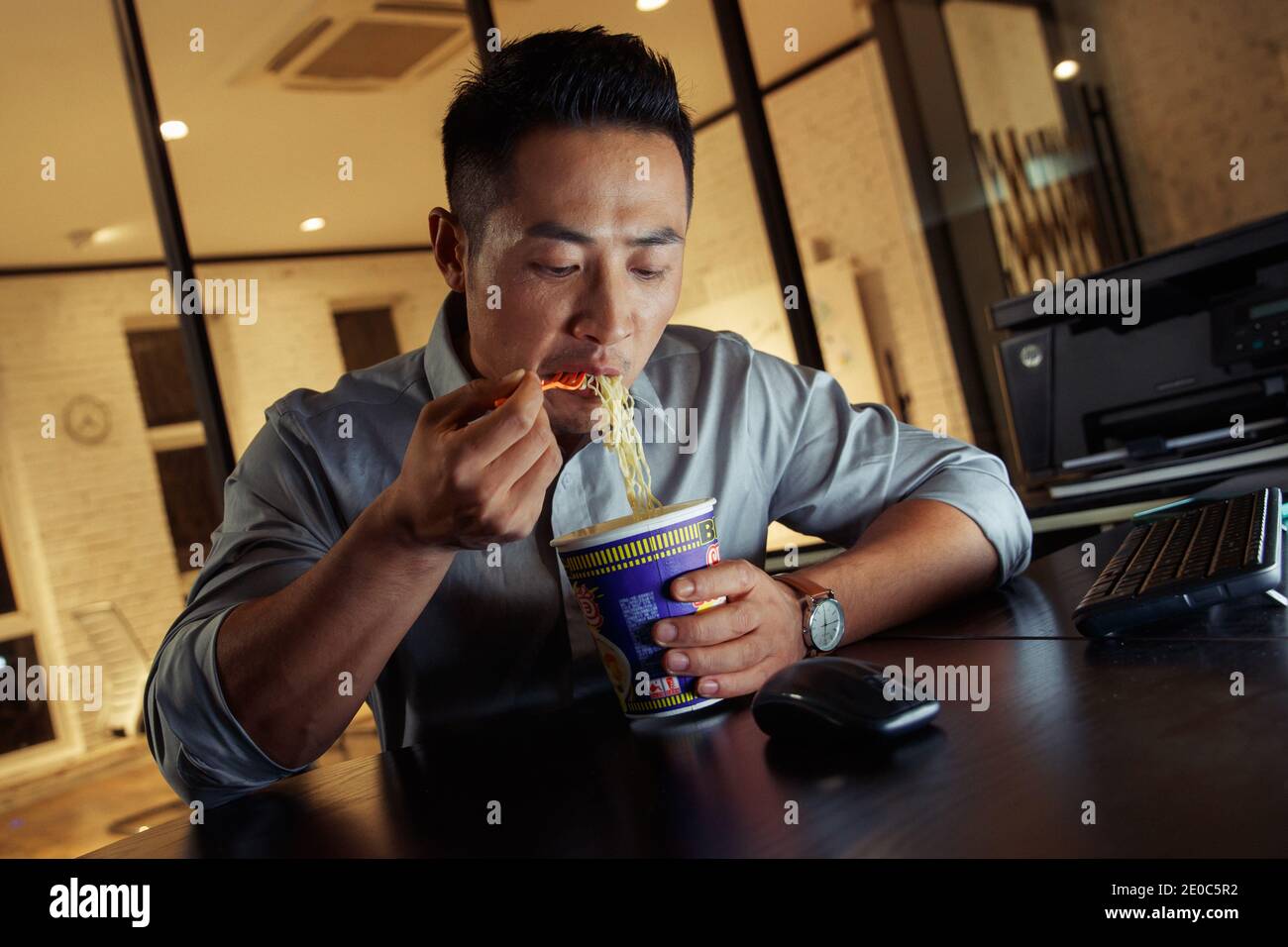 Young men in the office to work overtime to eat instant noodles Stock ...