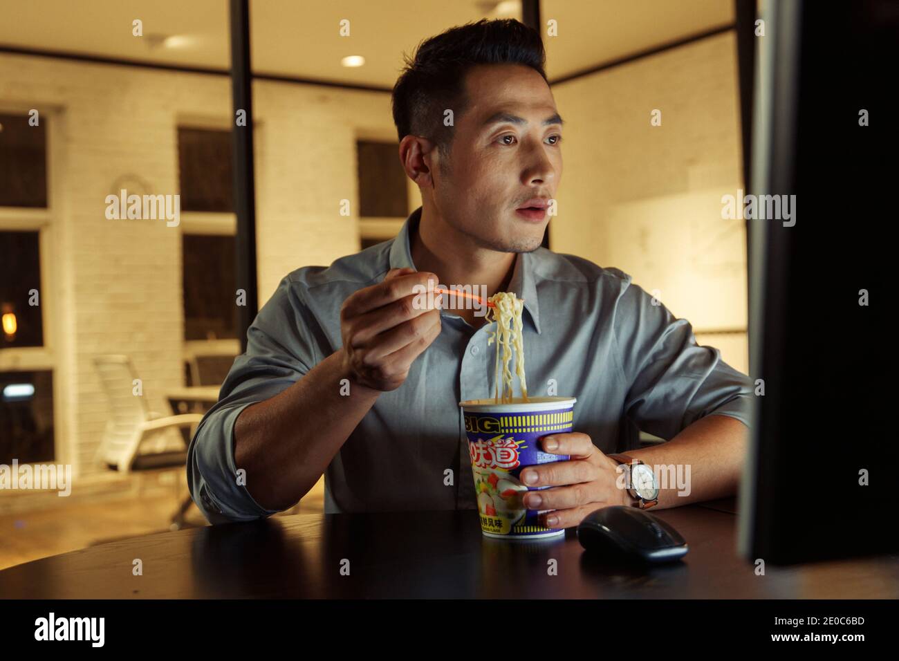 Young men in the office to work overtime to eat instant noodles Stock ...