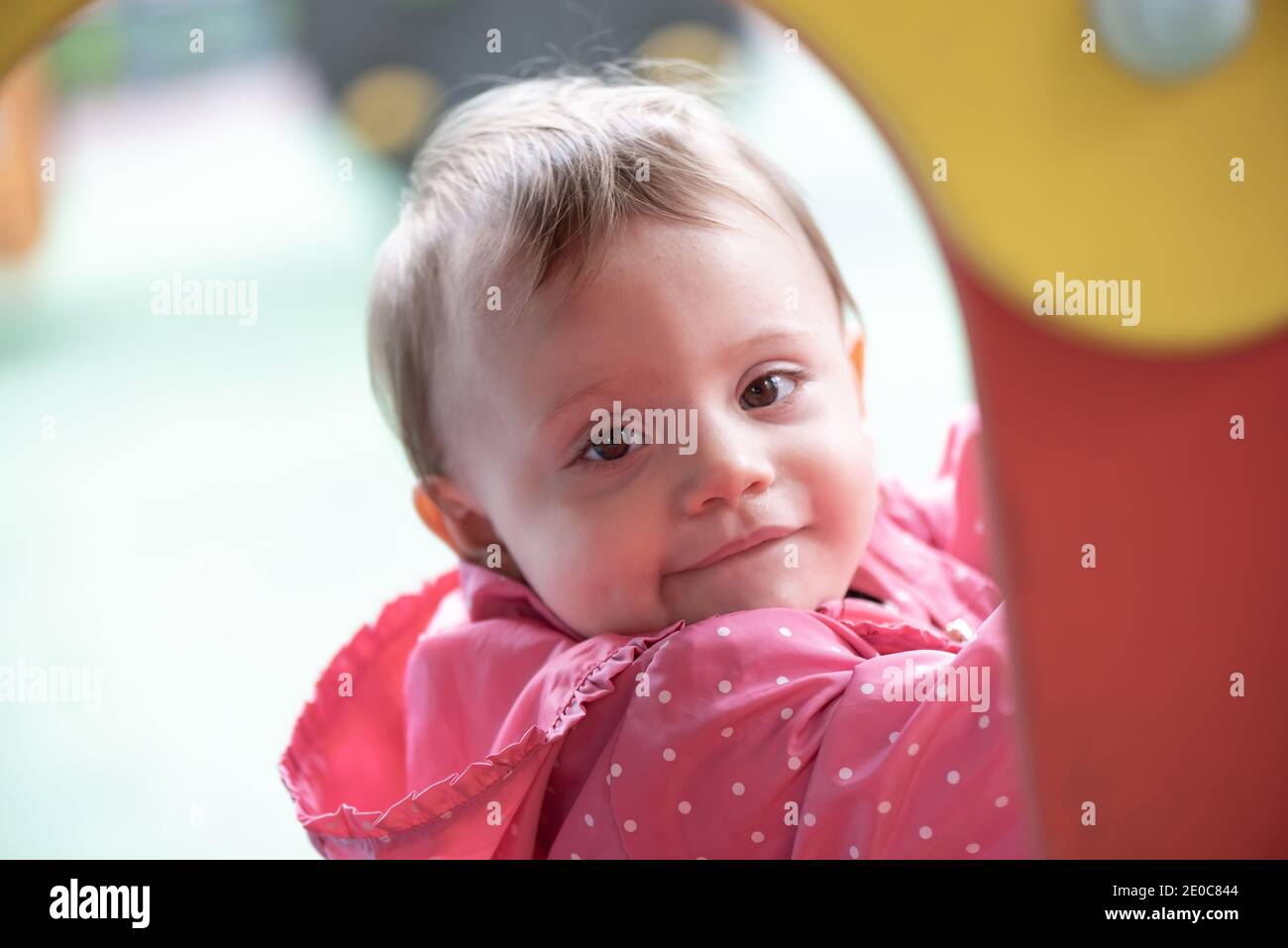 Cute baby girl having fun on a playground and looking at the camera ...