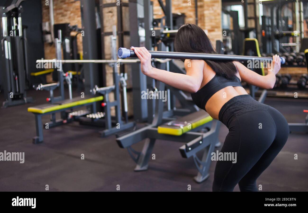 Slim brunette athlete doing gymnastic exercise with body bar on her ...