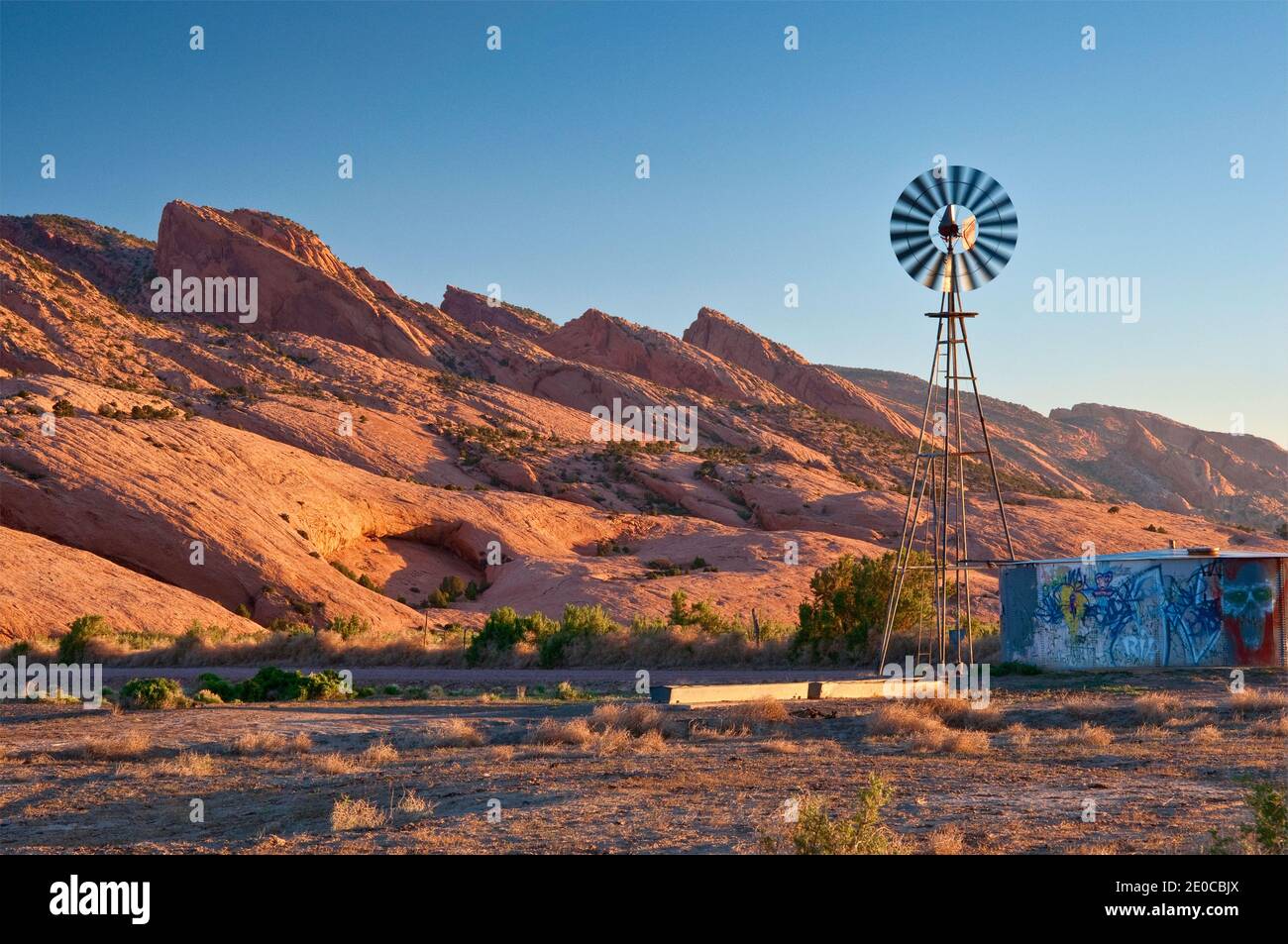 Windmill and water tank, Skeleton Mesa behind, at sunrise, Navajo ...